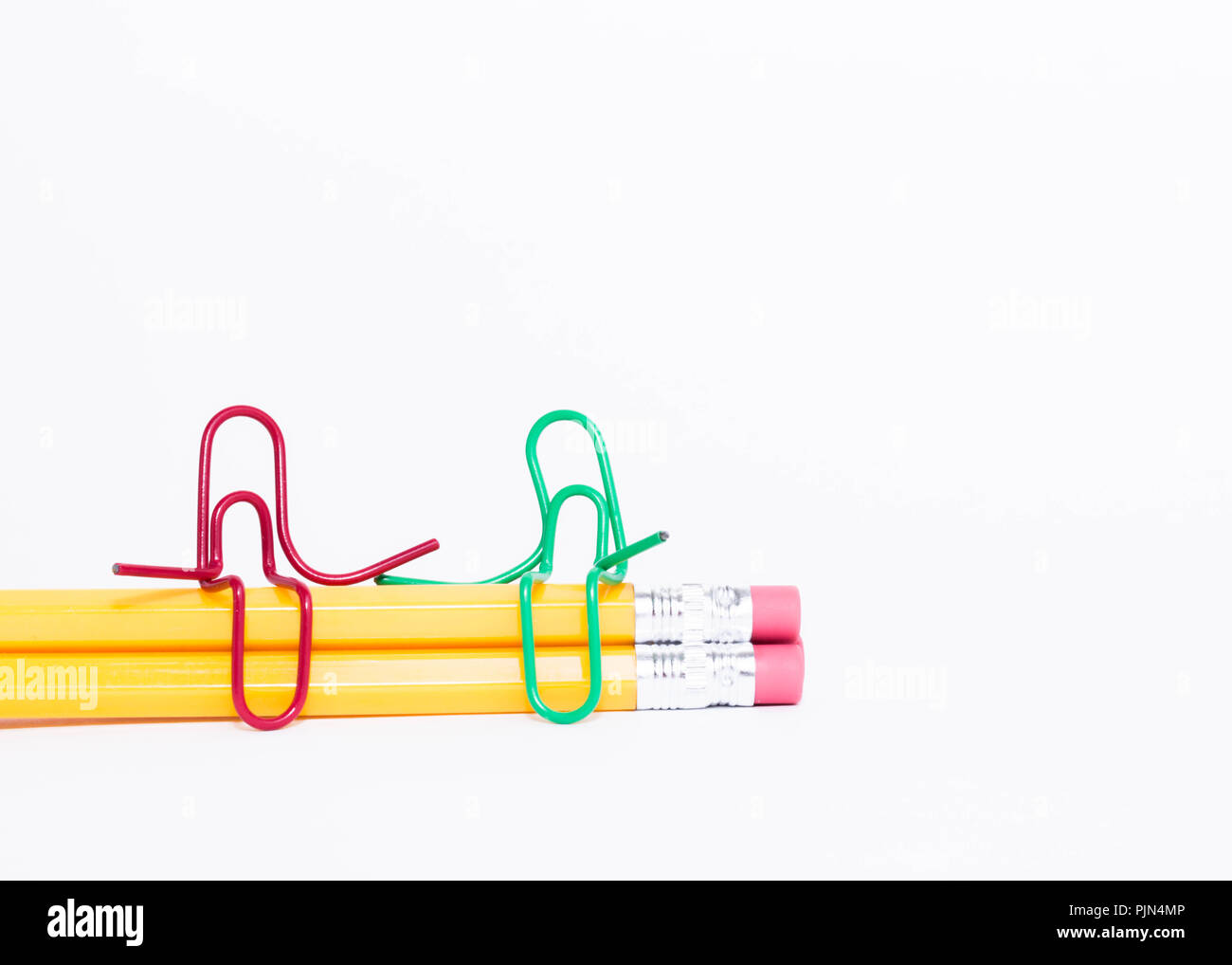 Two paper clips talking, having conversation while sitting on a pile of ...