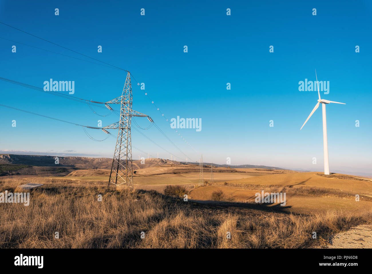 Windmill and electricity pylon on blue sunset sky Stock Photo - Alamy