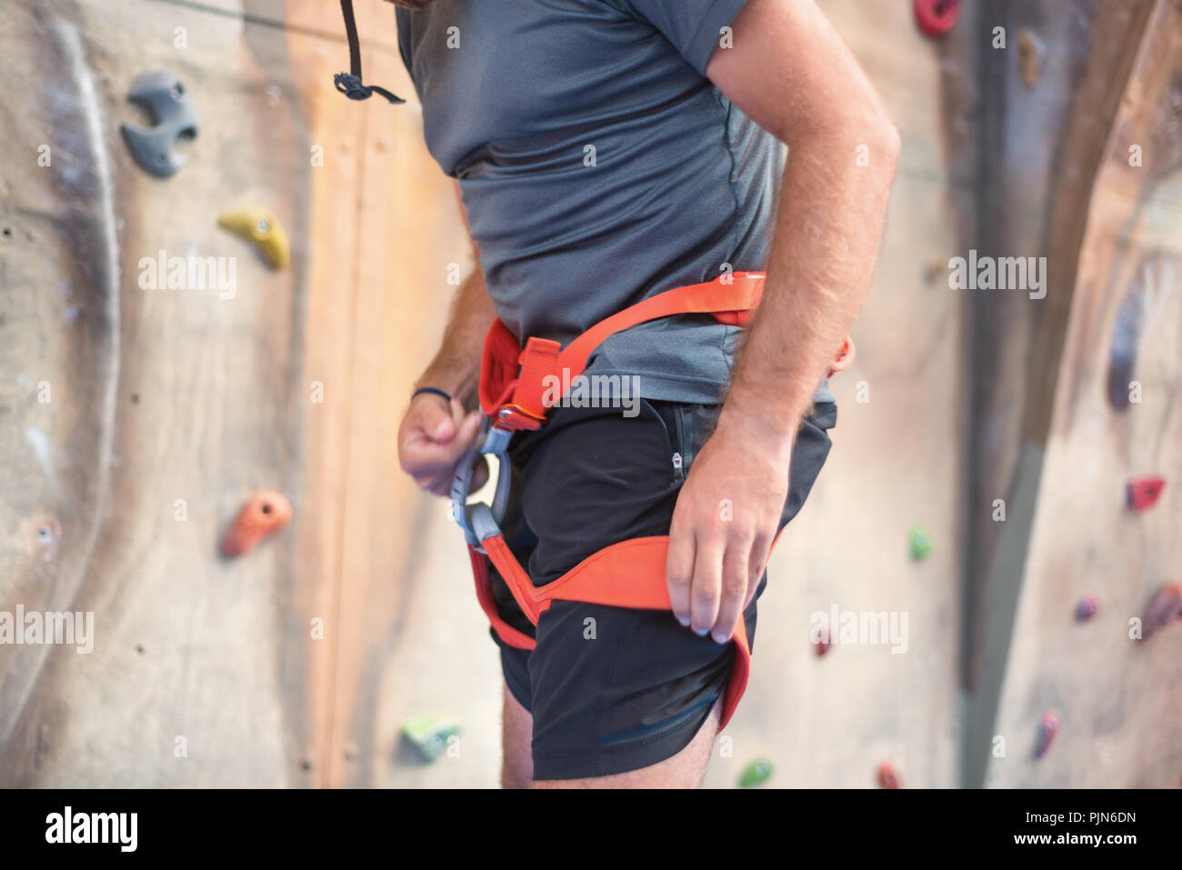 Rock wall climber wearing safety harness and climbing equipment indoor ...