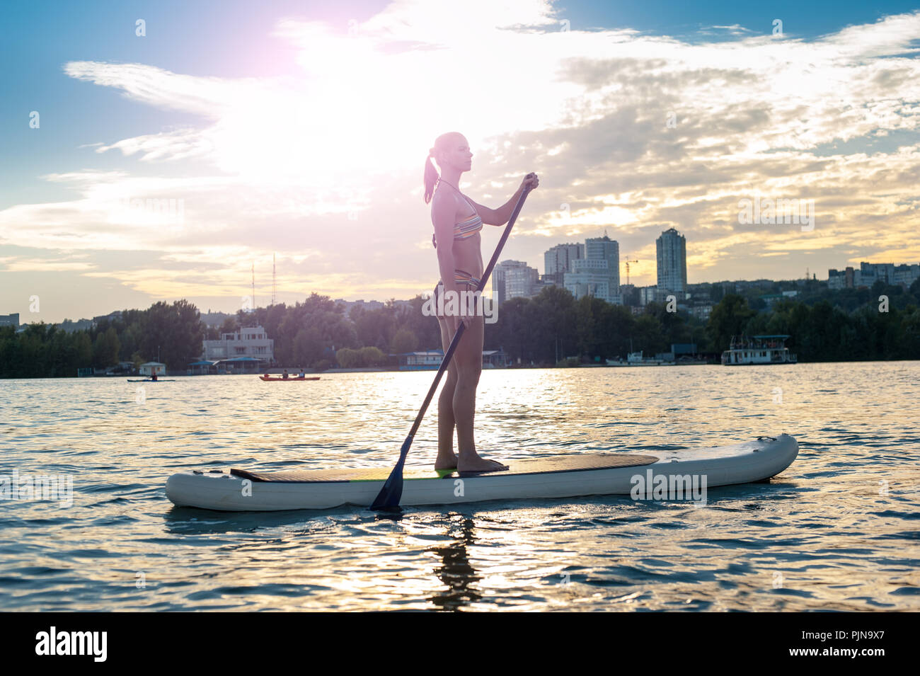 SUP confident woman swimsuit standing with a paddle on the surfboard Stock Photo - Alamy