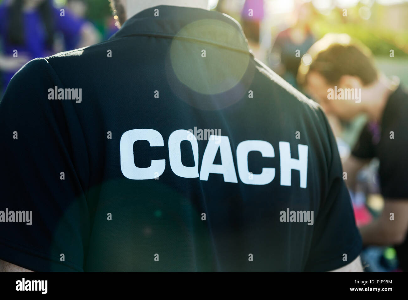 Sport coach in black shirt with white Coach text on the back standing ...