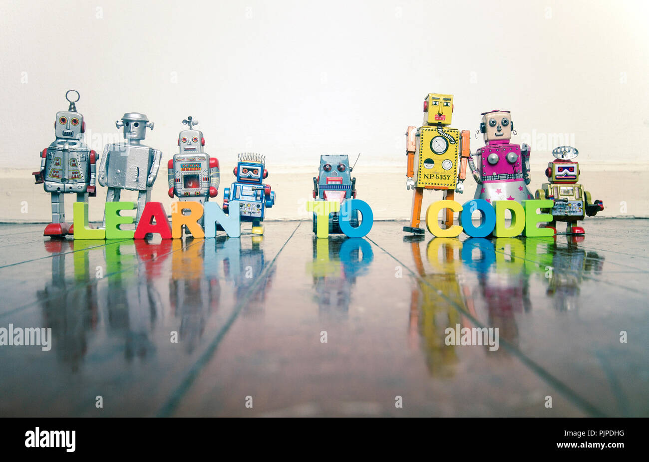 LEARN TO CODE wooden letters and retro robot toys on a wooden floor ...