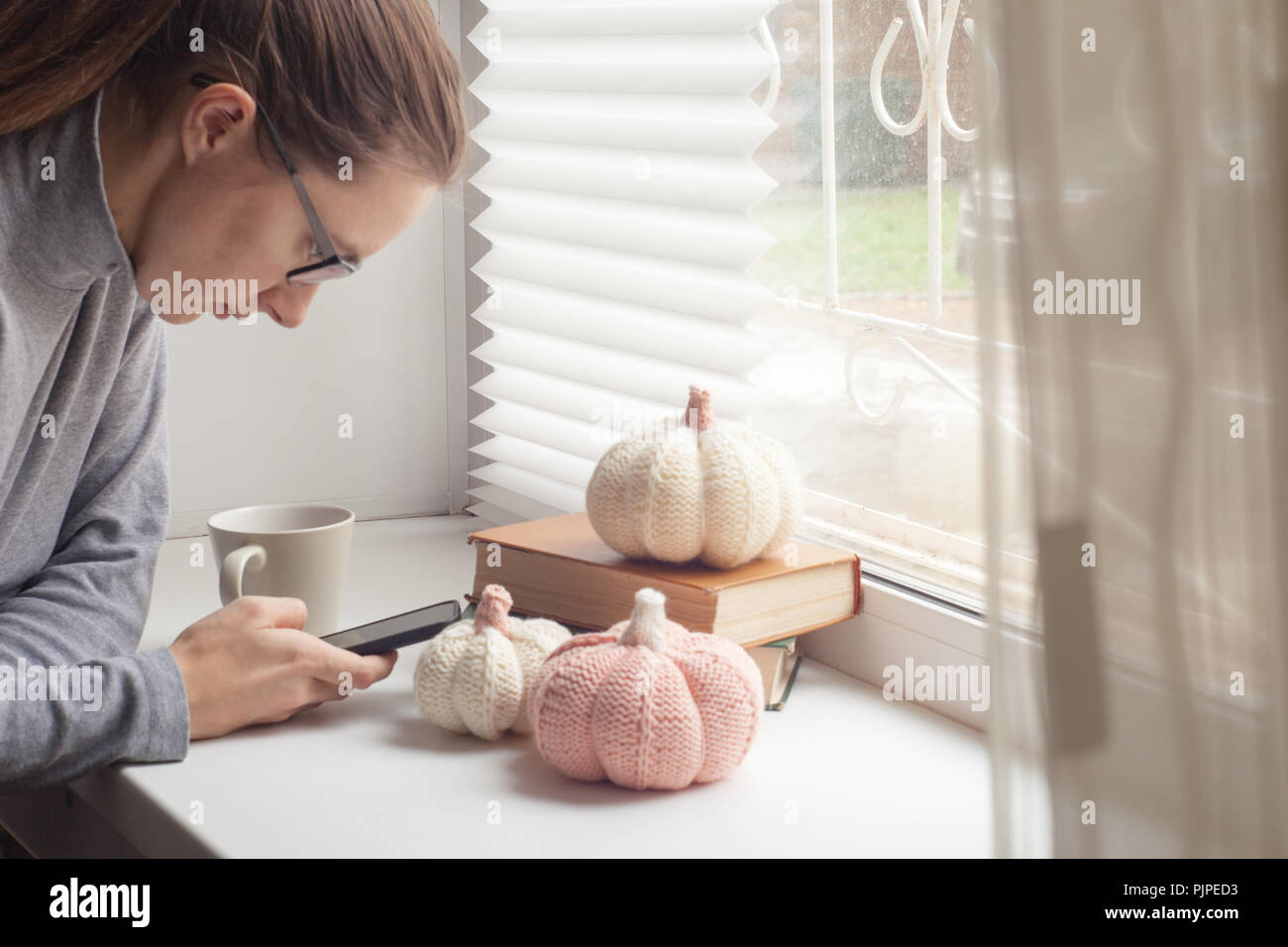 Cup of tea and chill. Woman lholding phone, drinking hot coffee and ...