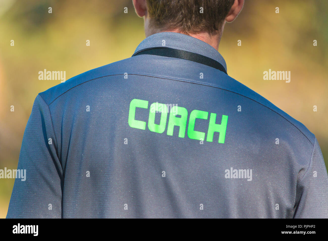 Back of sport coach wearing sport shirt with word Coach written on back ...