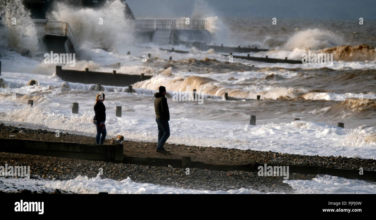 Two people on a beach with very strong weather conditions and dangerous ...