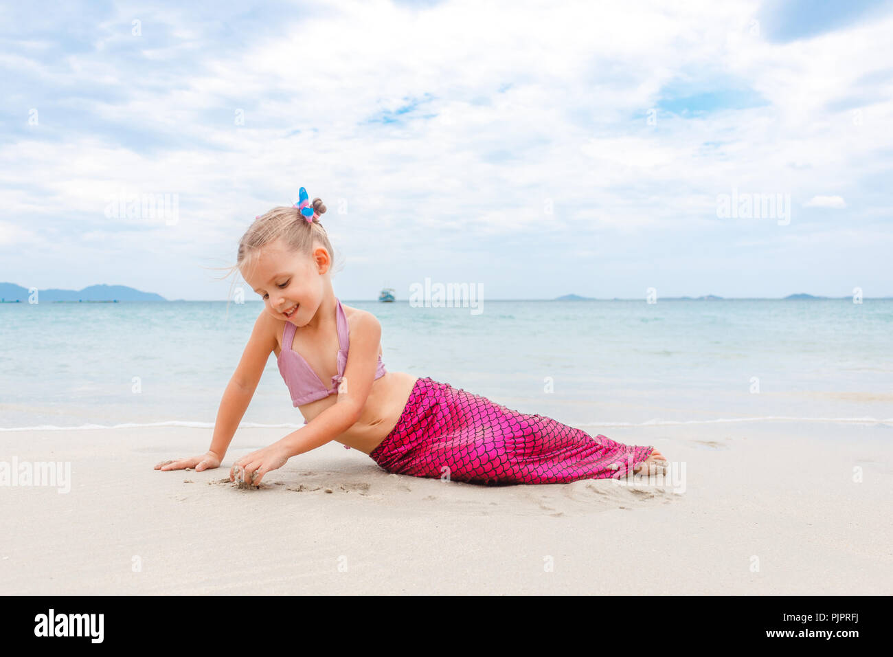 Little beautiful girl dressed in swimsuit as a mermaid sits on the ...