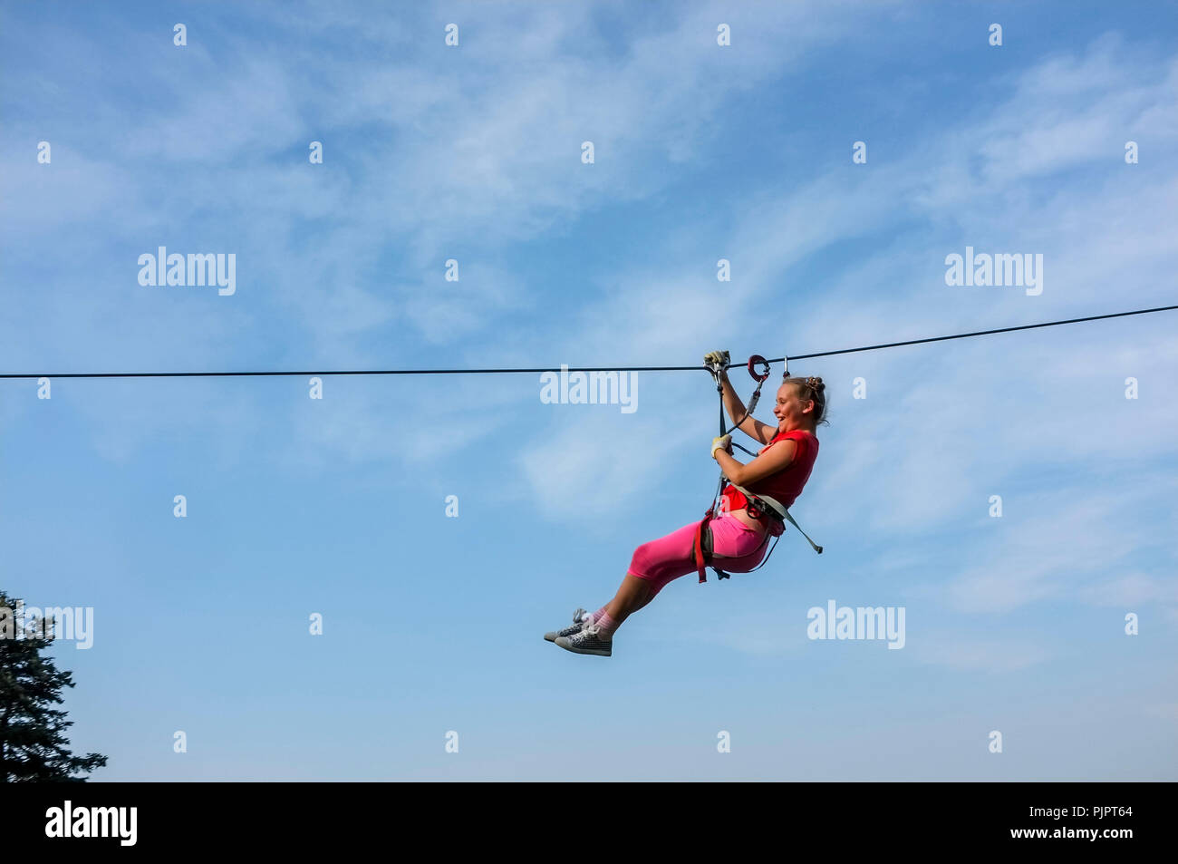 Pre-teen girl on a zip line against the sky Stock Photo - Alamy