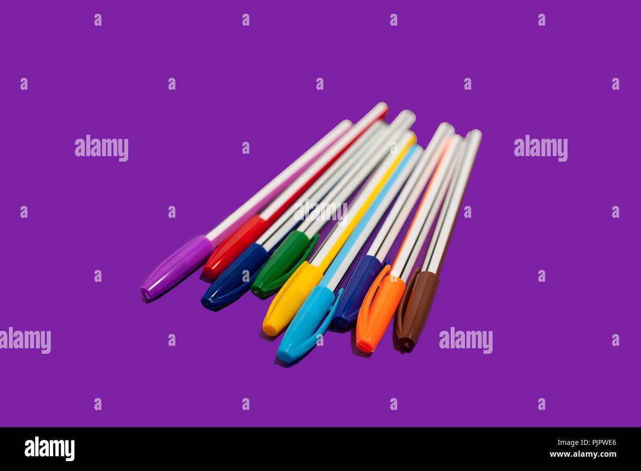 different new bright colored pens lying on a purple background. concept ...