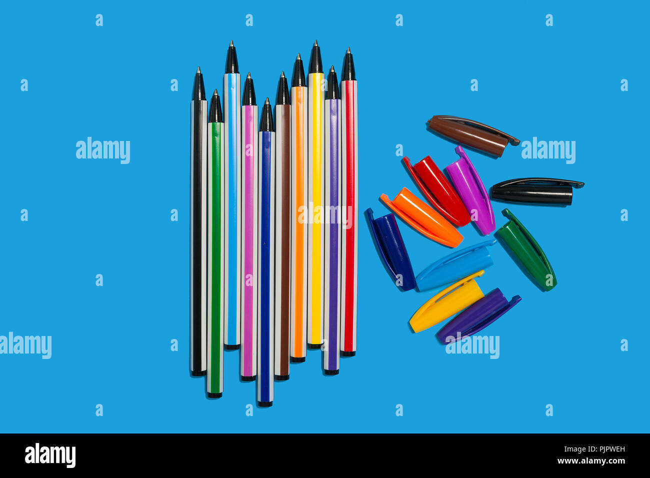 different new bright colored pens lying on a blue background without ...
