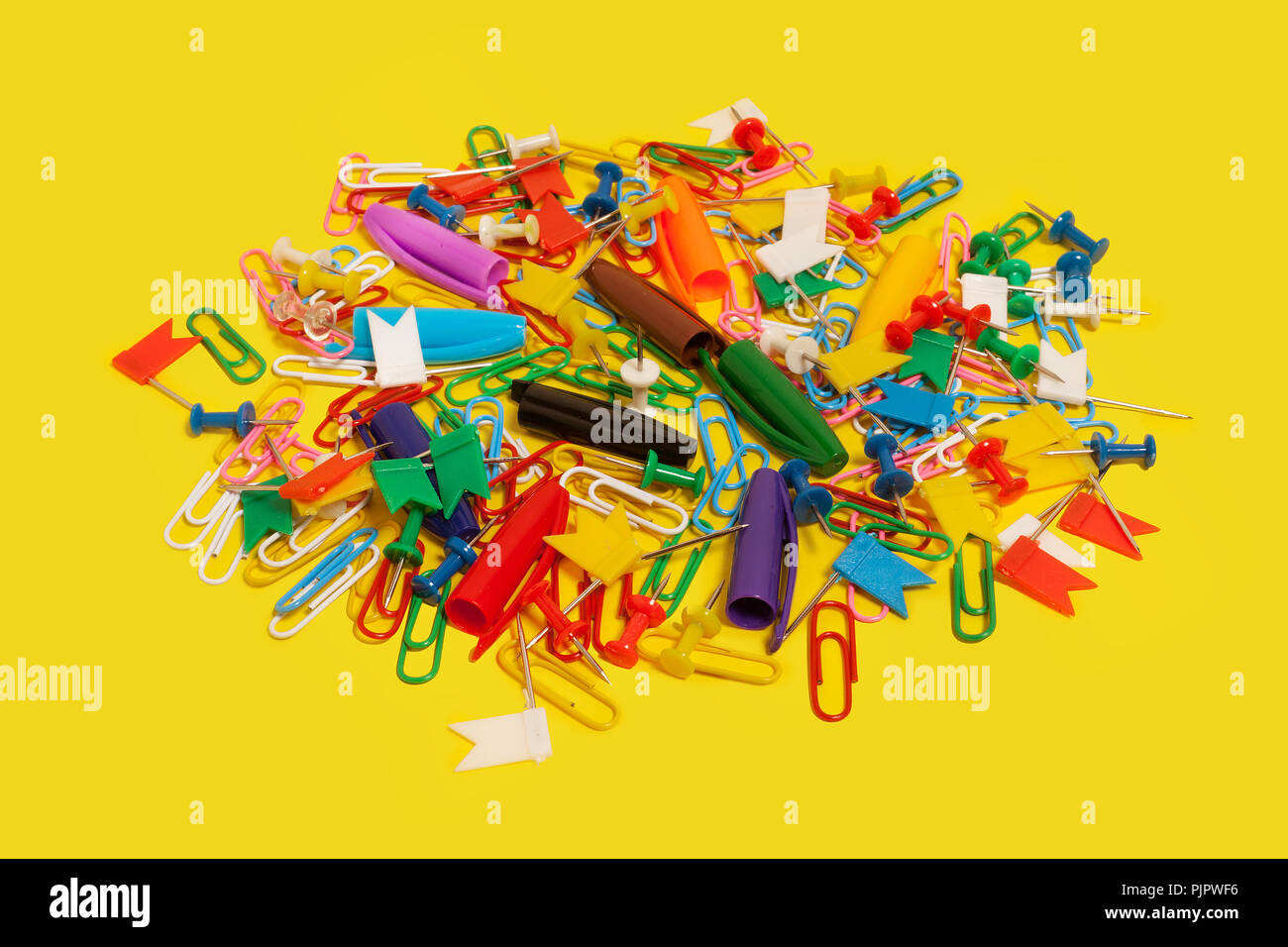 collection of colored pushpins, paper clips and pen caps lying on a ...