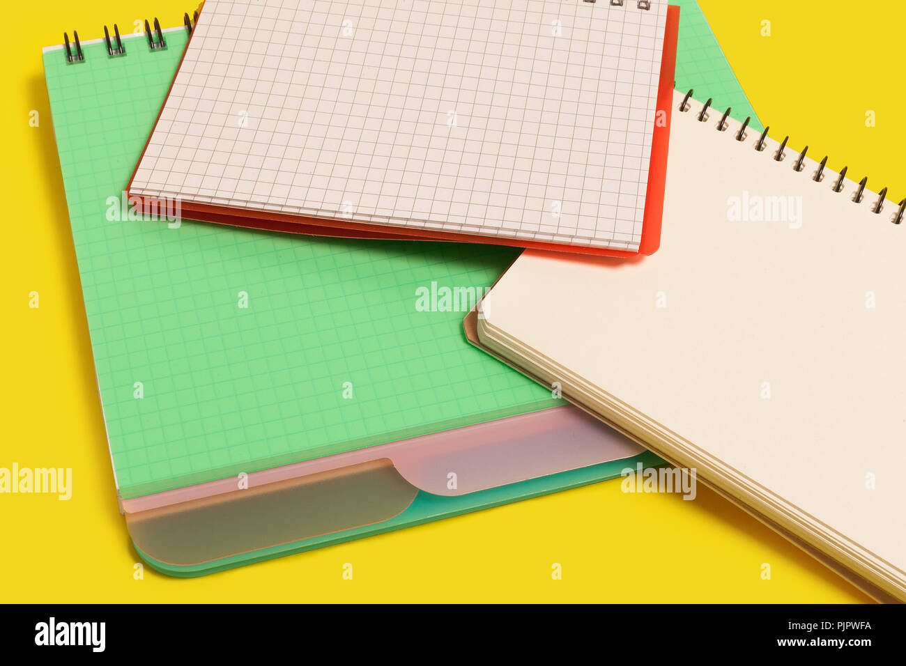 pile of spiral notebooks lying on a yellow background. concept of ...