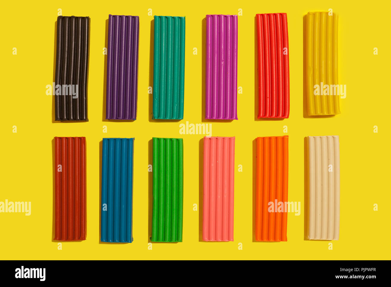 Set of colorful plasticine sticks lying on a yellow background ...