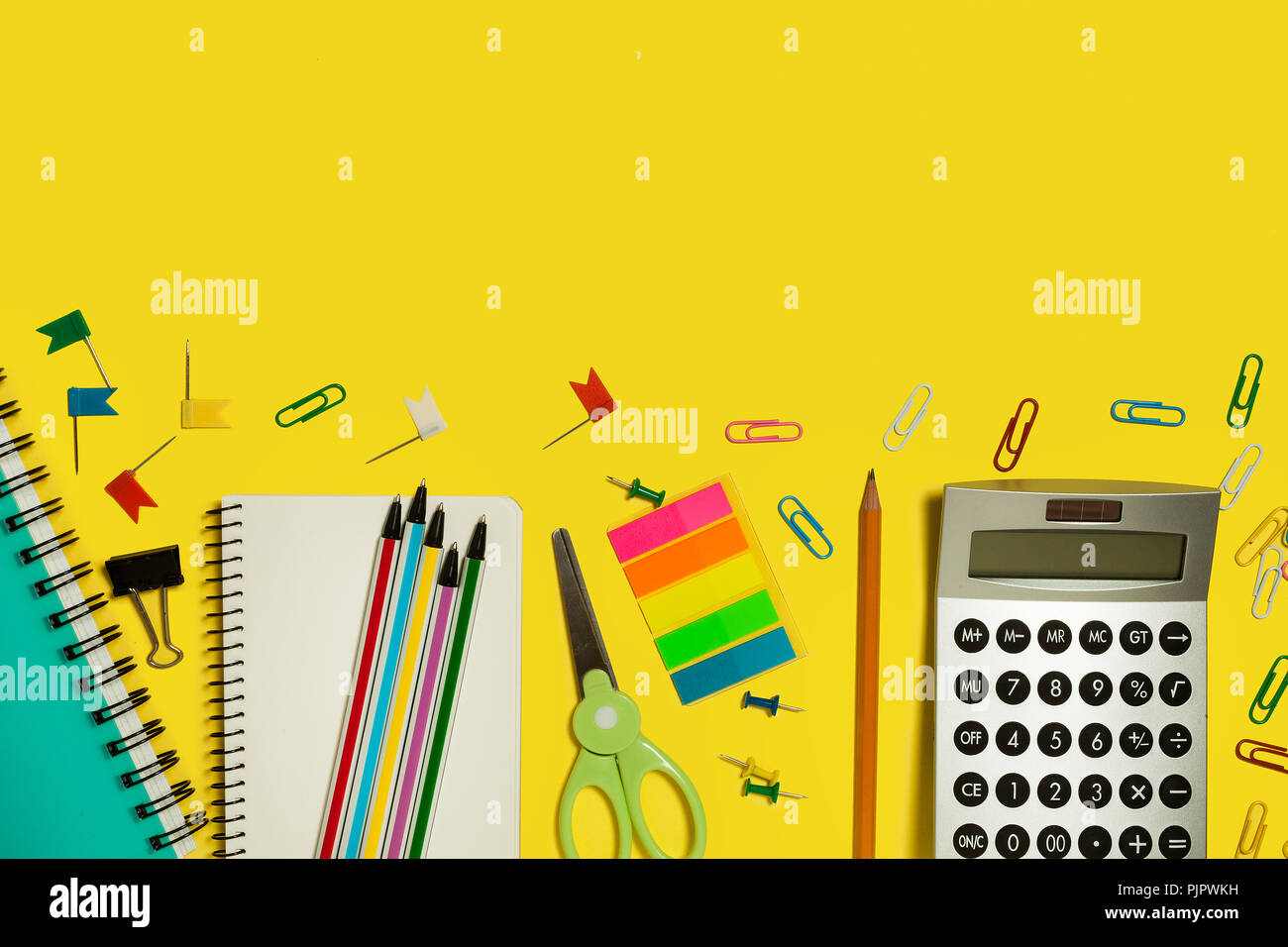 multiple school and office suplies and gadgets lying on a yellow ...