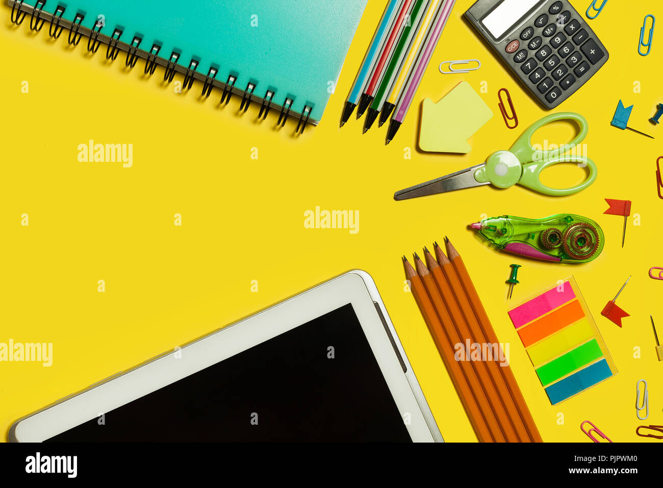 various school and office suplies and gadgets lying on a yellow ...