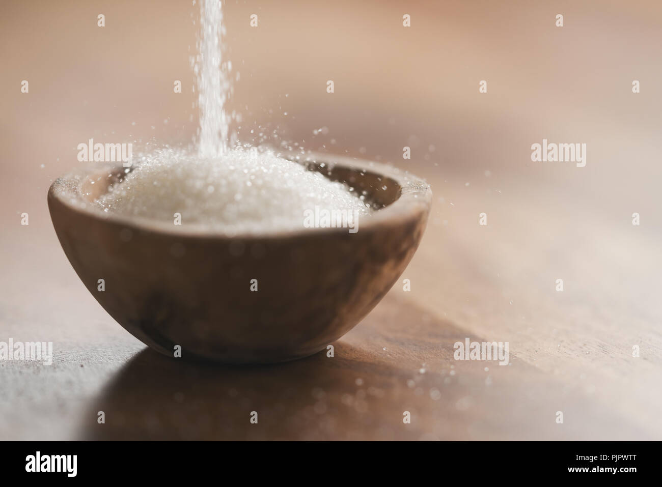 White sugar falling in wood bowl on table, shallow focus Stock Photo ...