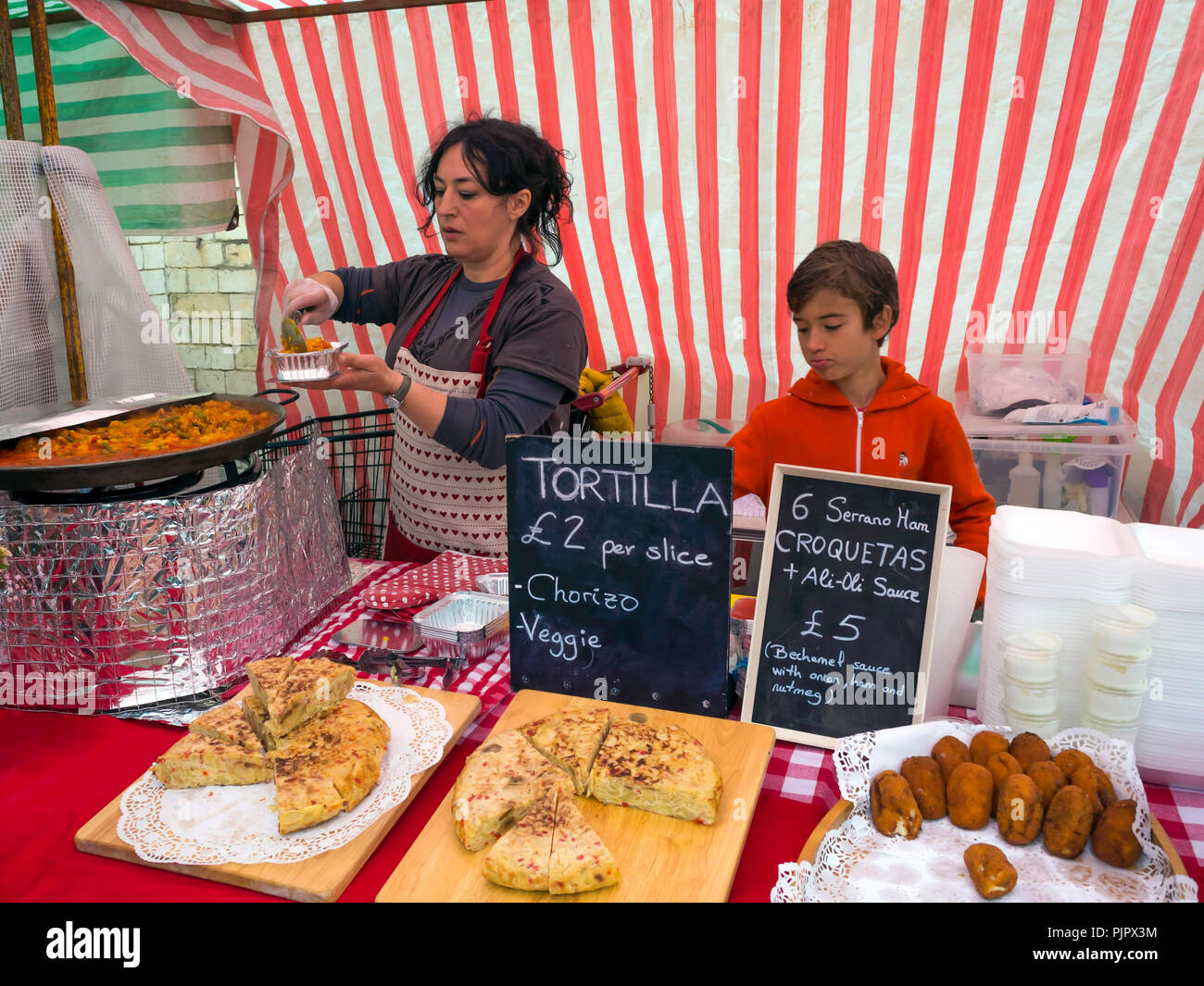 A Spanish woman stall holder at a UK farmer's market serving a portion ...