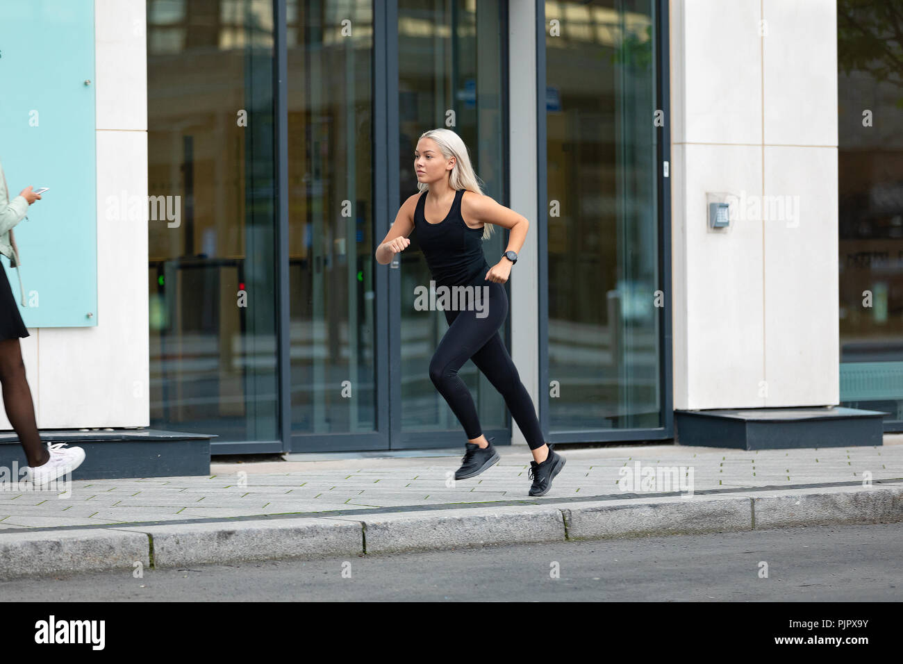 Side view of sporty woman running fast in minimalist urban environment ...