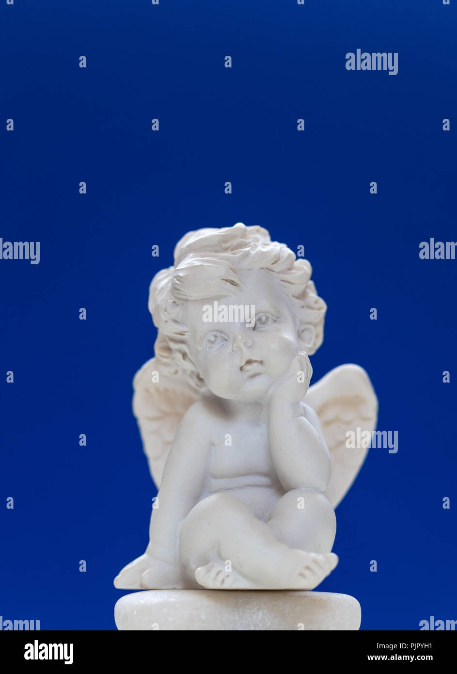 Figurine Of Baby Angel Isolated On Blue Background. Macro Photography ...