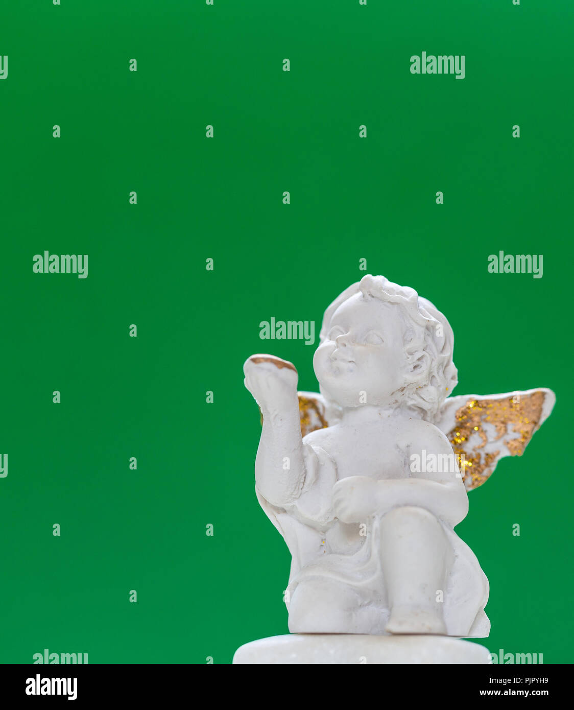 Figurine Of Baby Angel Isolated On Green Background. Macro Photography ...