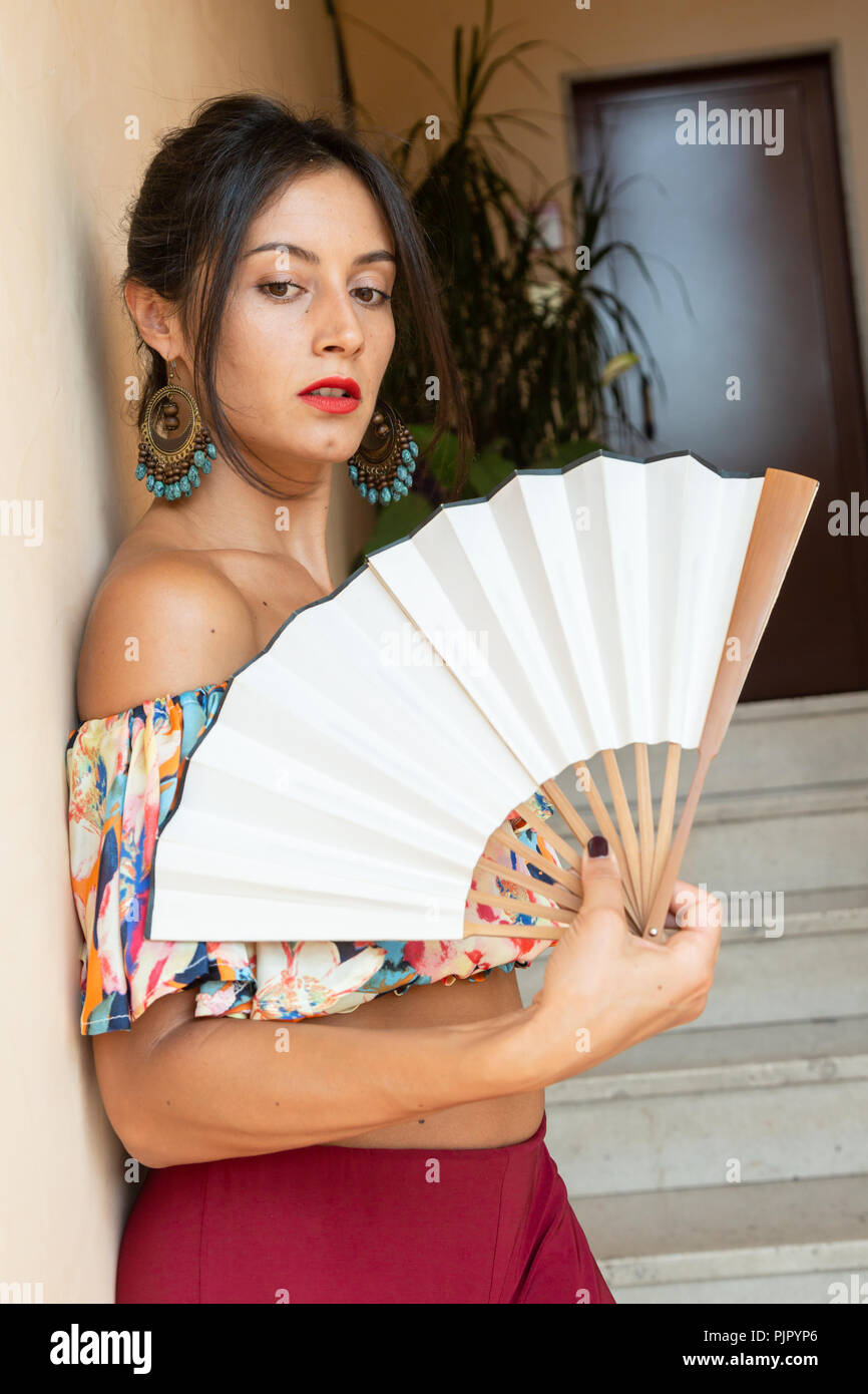 Portrait of a beautiful young brunette holding a fan Stock Photo - Alamy
