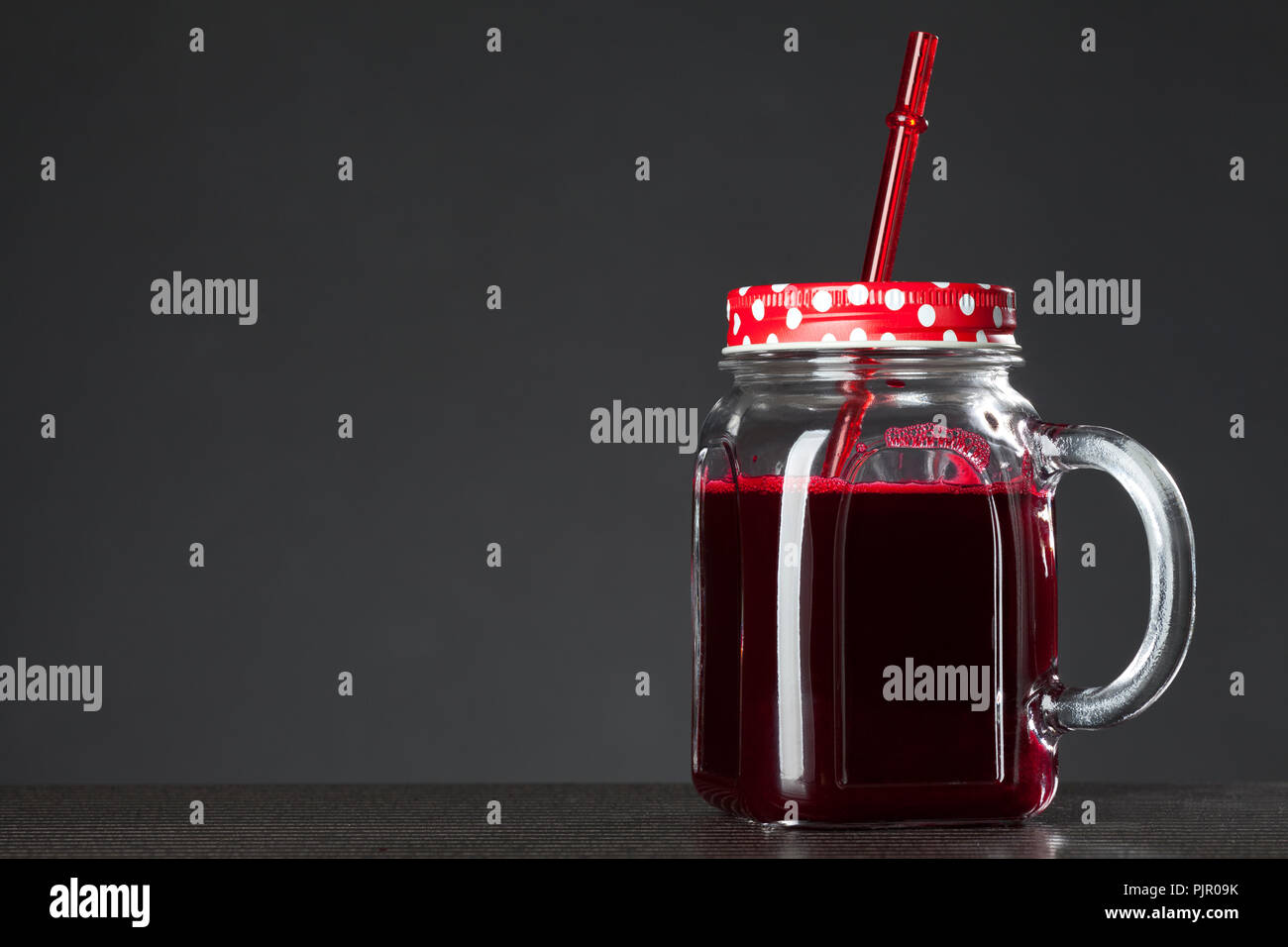 red vegetable or fruit juice in glass jar on black background with ...