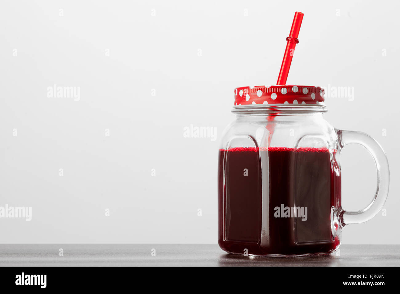 red vegetable or fruit juice in glass jar on black background with ...