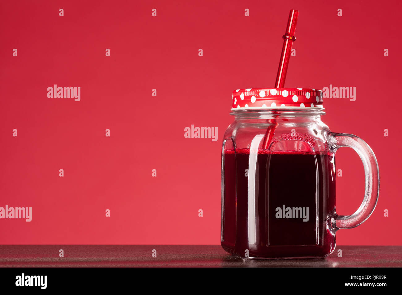 red vegetable or fruit juice in glass jar on black background with ...