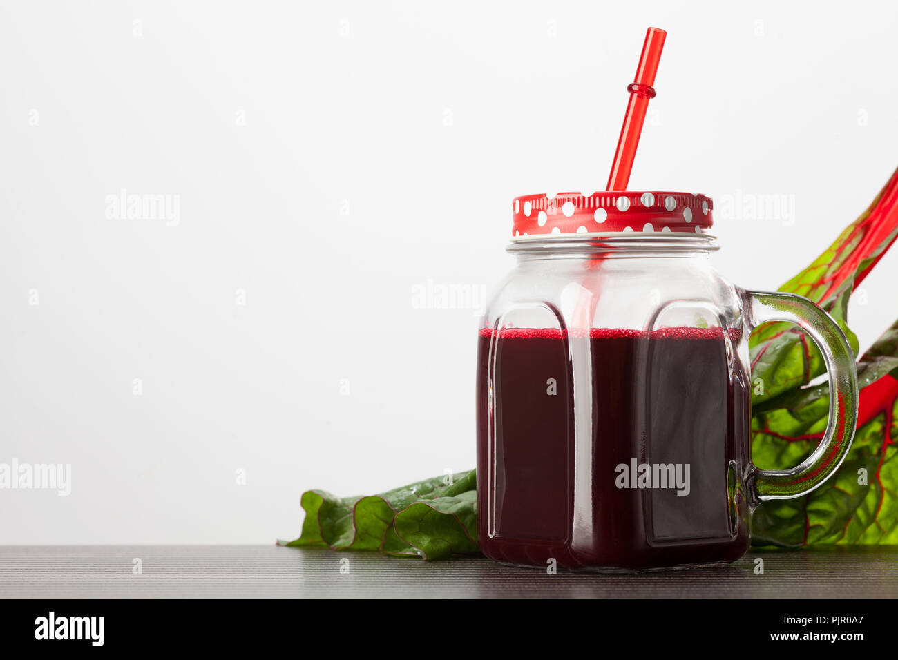red vegetable or fruit juice in glass jar on white background with ...