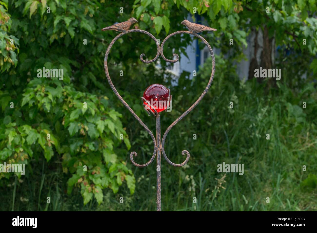 Heart-shaped garden plug decorated with a red glass ball Stock Photo ...