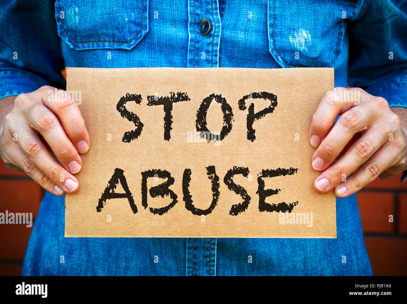Woman hands holding piece of cardboard with words Stop Abuse against ...