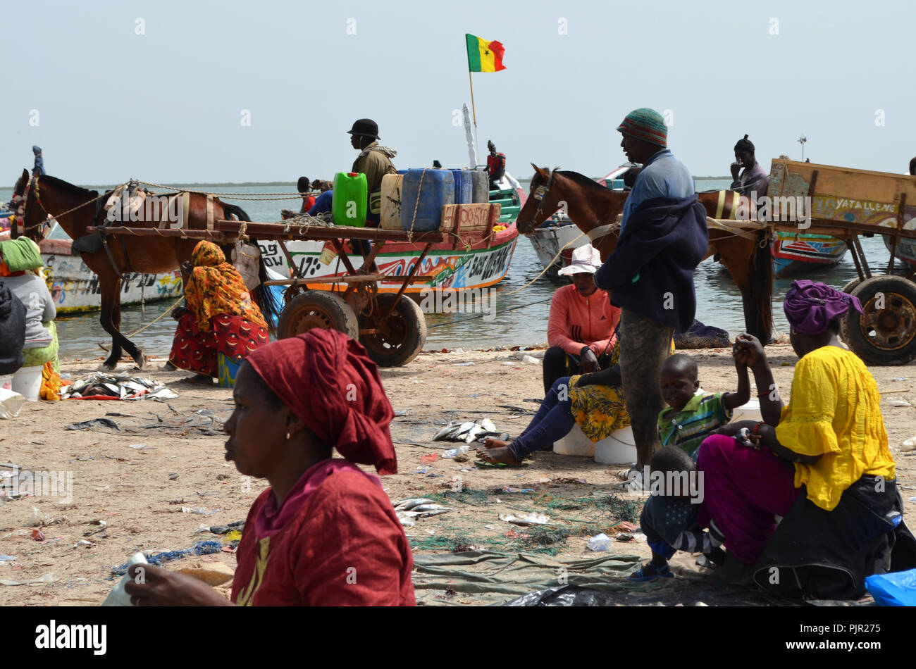 A crowded beach in Mbour, Senegal, with fishers landing their catch and ...