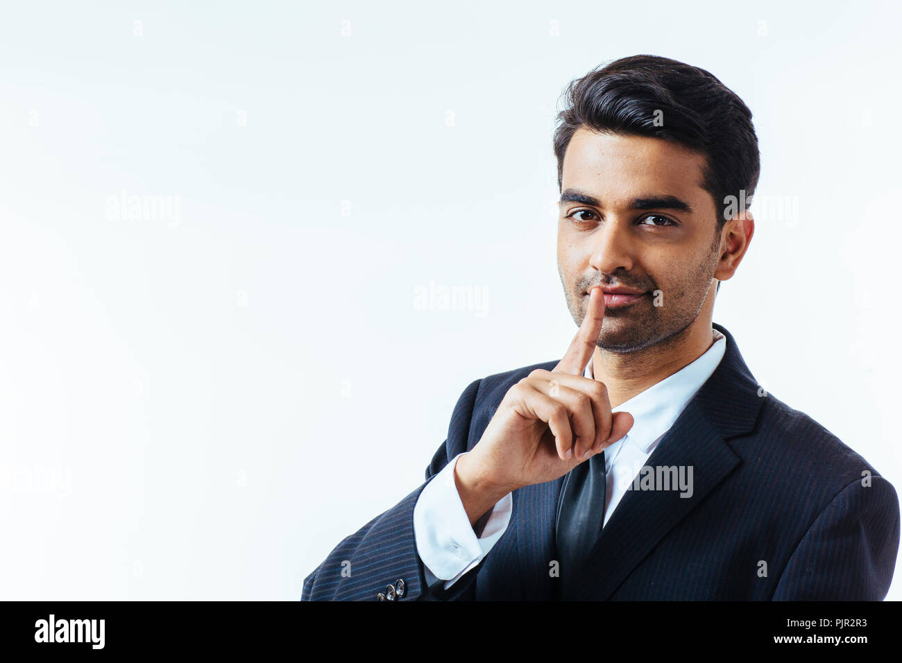 Portrait of a good looking businessman with one finger on his mouth ...