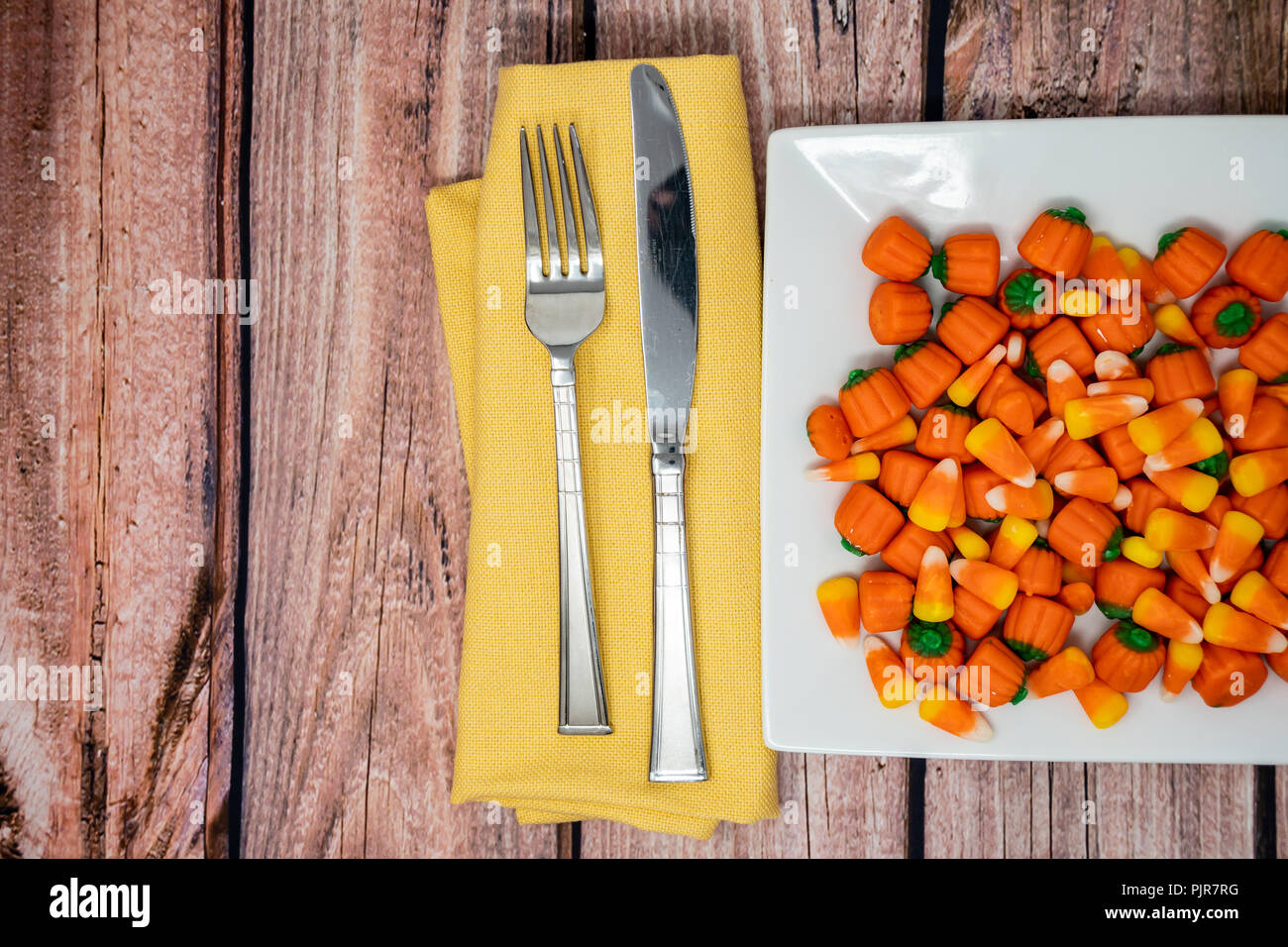 Plated view of candy corn and candy pumpkins with fork and knife on ...