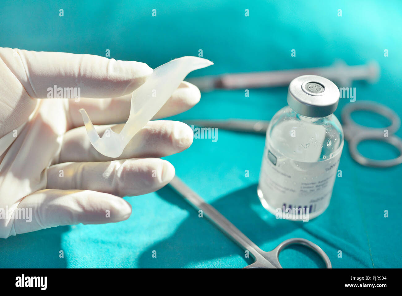 Hand holding silicone nasal implant in operating room with surgical ...