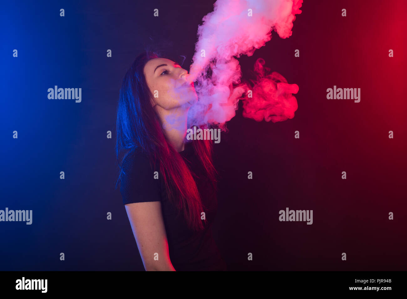 Portrait of asian woman smoking vape or e-cigarette in neon light at ...