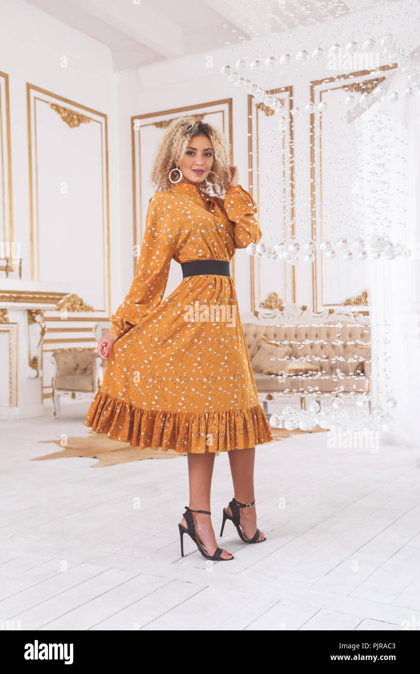 Beautiful charming ethnic woman in dress standing in elegant interior ...