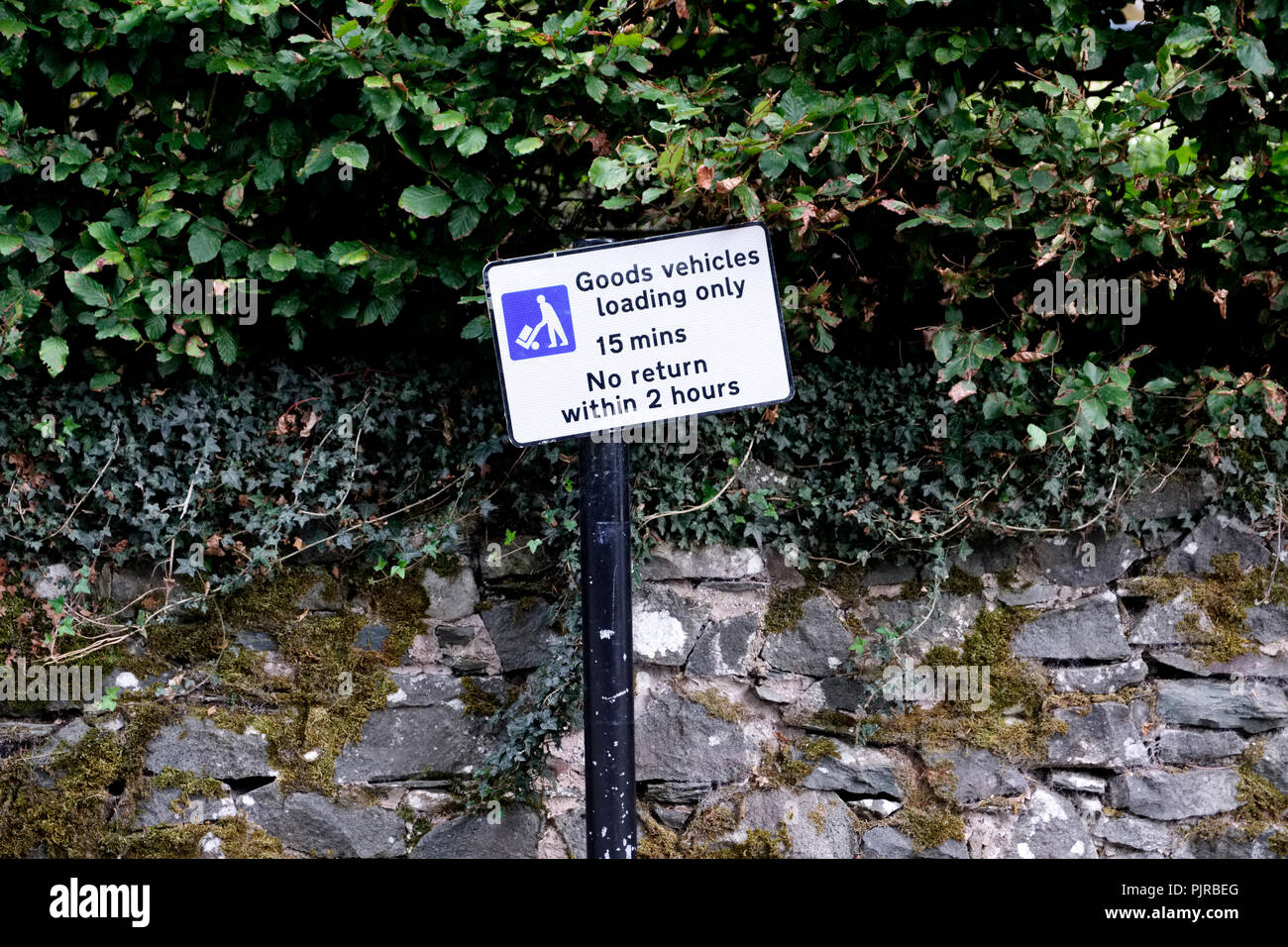 Goods vehicles loading only no return sign post wall and hedge Stock ...