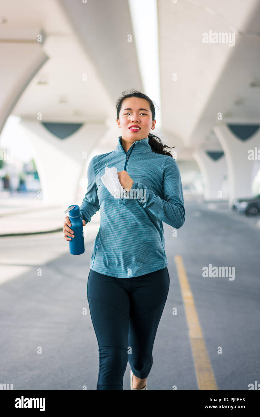 Girl running bellow the bridge at car park in urban area Stock Photo ...
