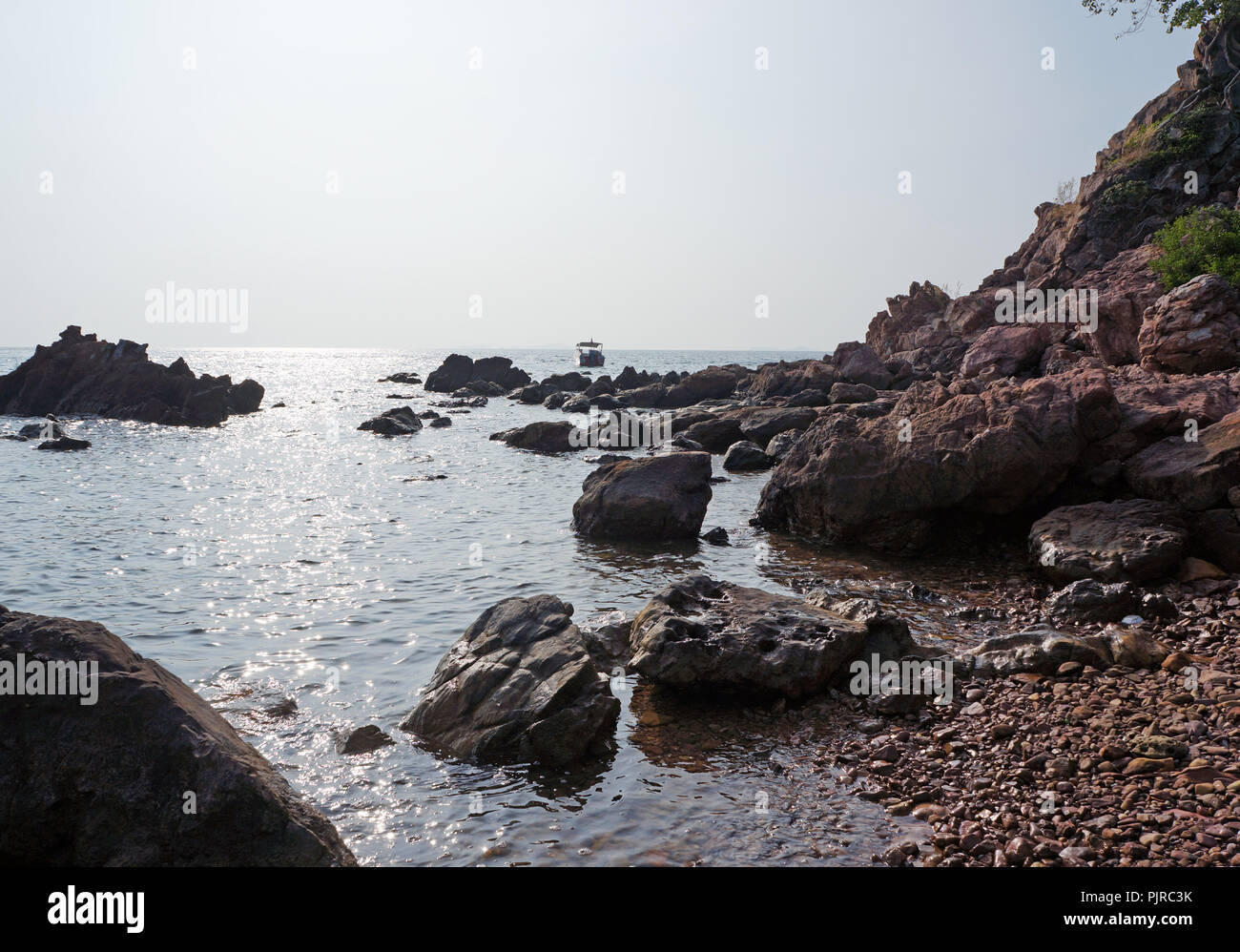 View of the sea with boat from the rocky coastline rocks Stock Photo ...