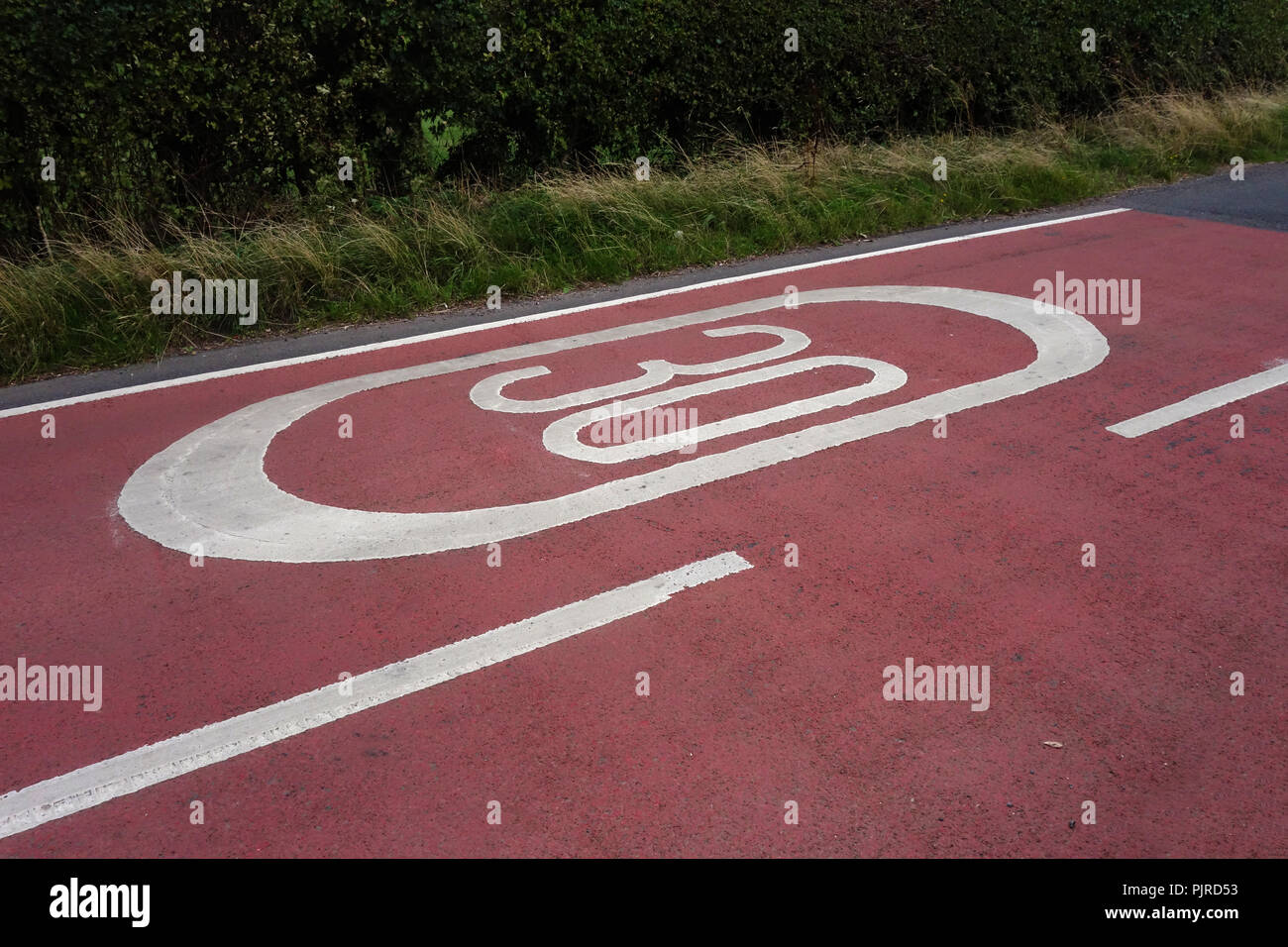 massive 30 symbol on a red covered road in 30 miles an hour speed limit ...