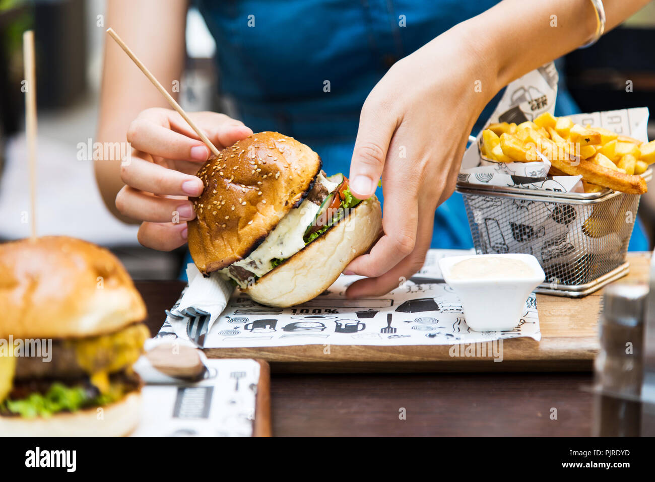Girl eating burger in the restaurant close up Stock Photo - Alamy