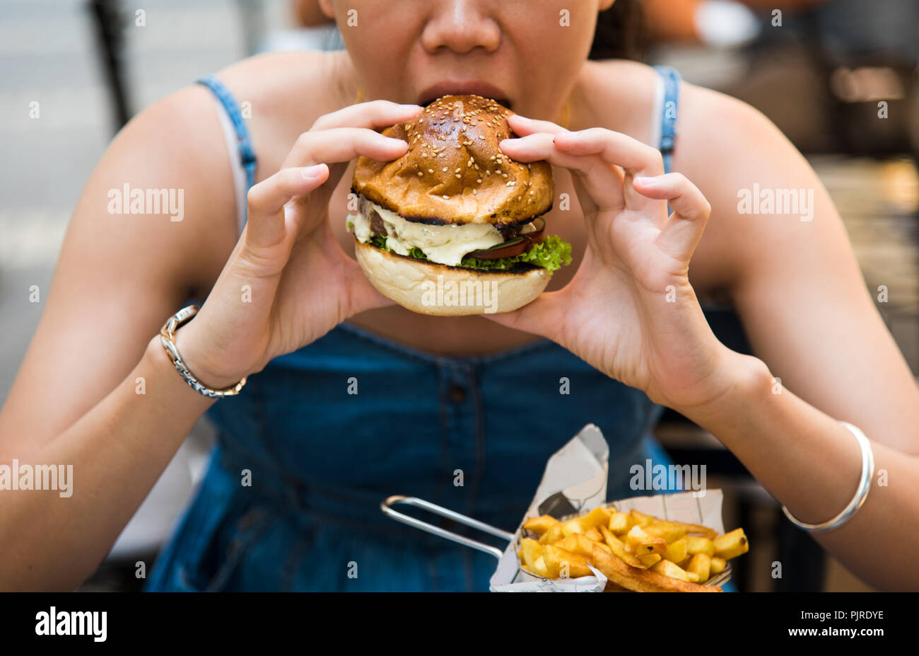 Girl eating burger in the restaurant close up Stock Photo - Alamy
