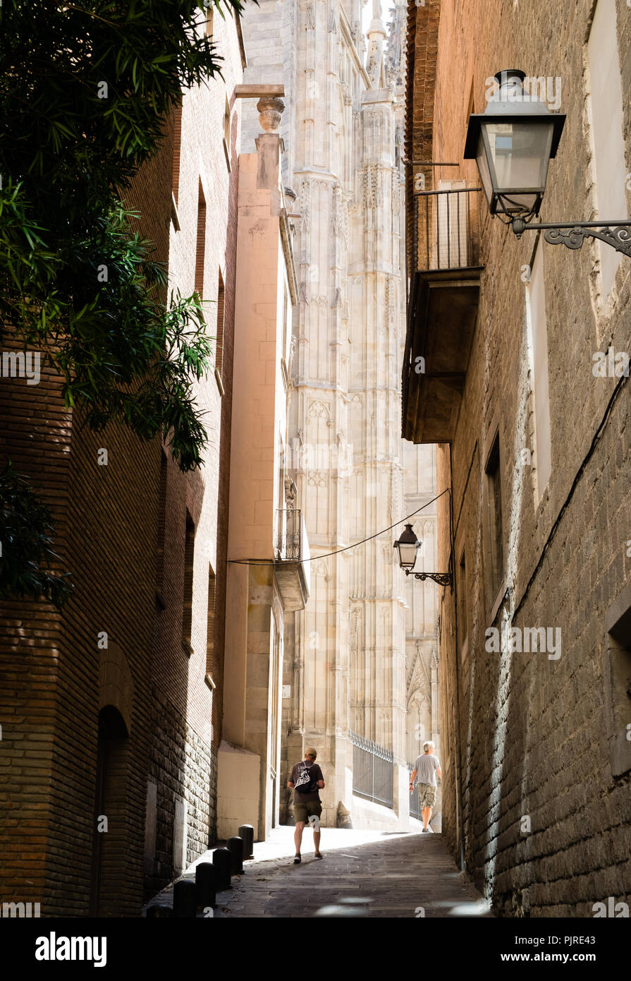 A man walking along a street with tall buildings looming over him ...