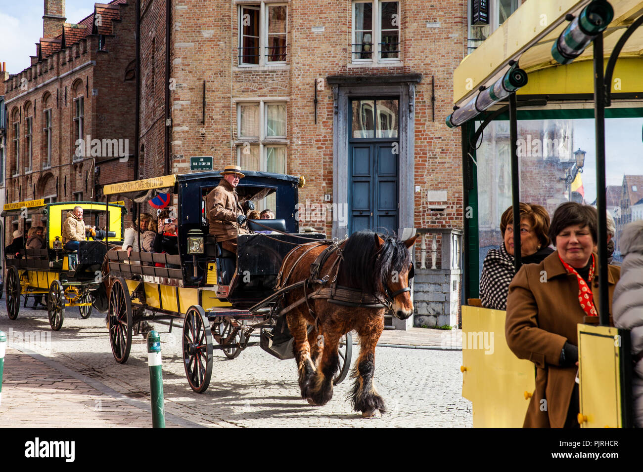 People touring around the beautiful Bruges town on a carriage pulled by ...