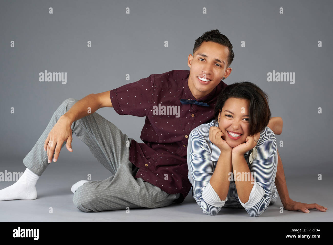 Happy young latin couple looking in to camera isolated on studio ...