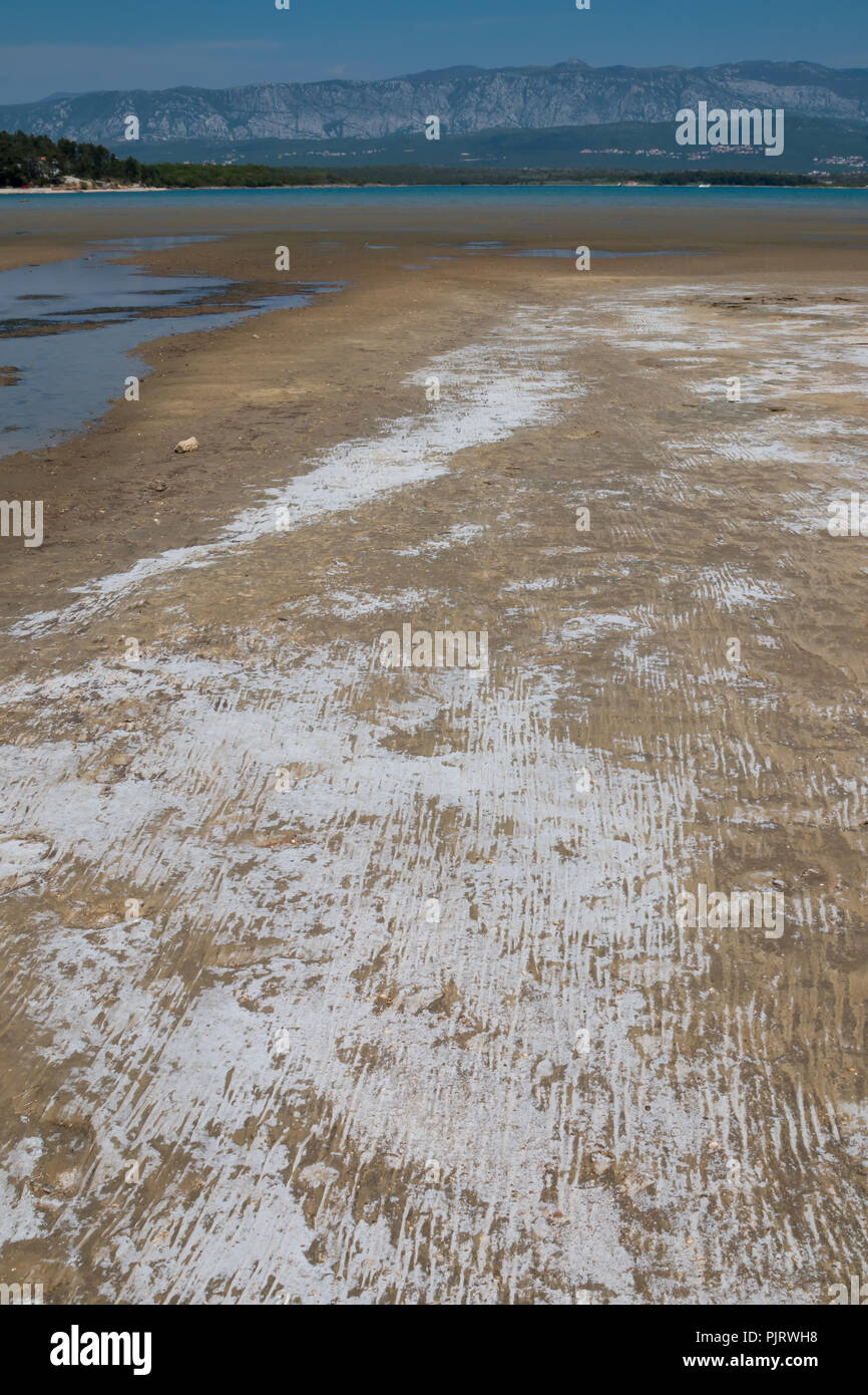Sandy beach at the coast of the Adriatic sea. Puddles from the high ...