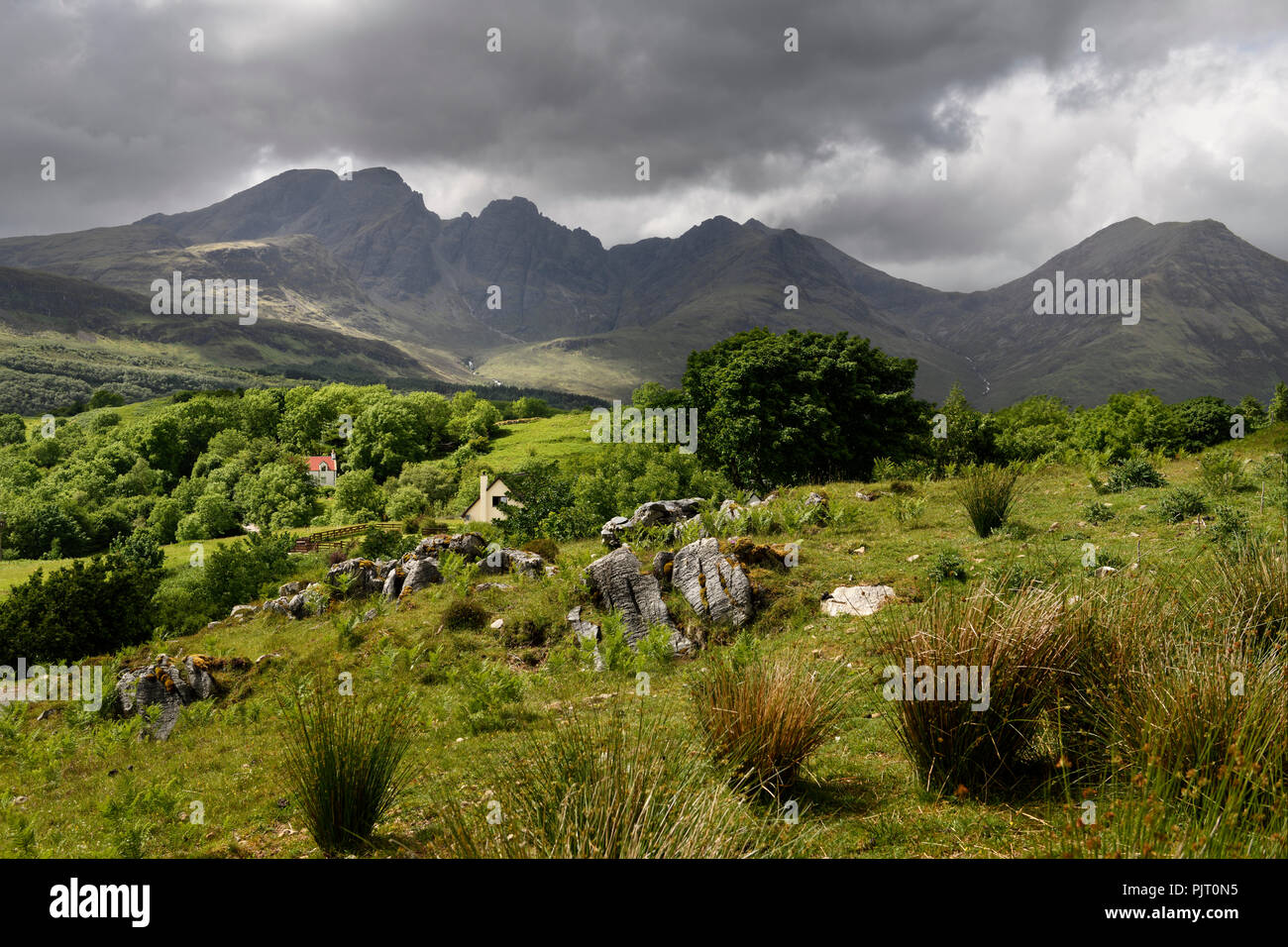 Dappled sun on Blaven mountains of Black Cuillin Hills under dark ...