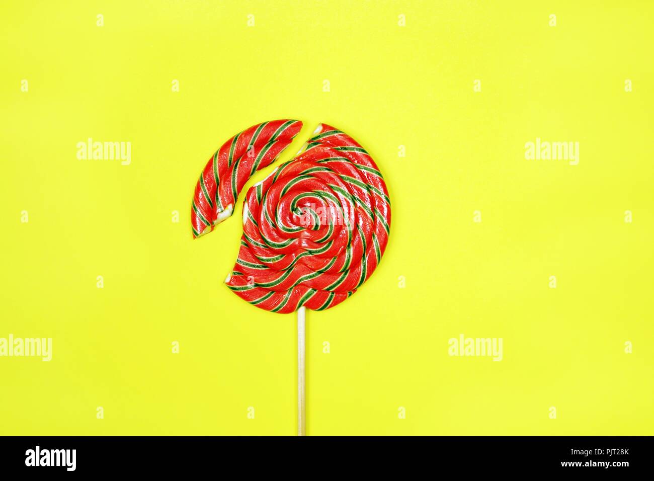 Broken lollipop on yellow background, top view Stock Photo - Alamy