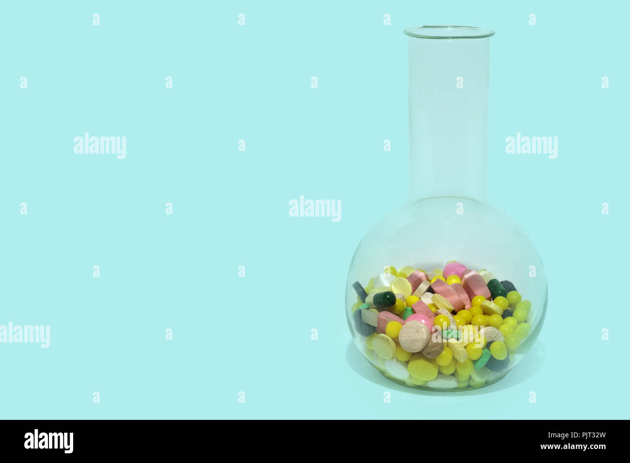 Florence flask, full of multicolored pills, on cyan background with ...