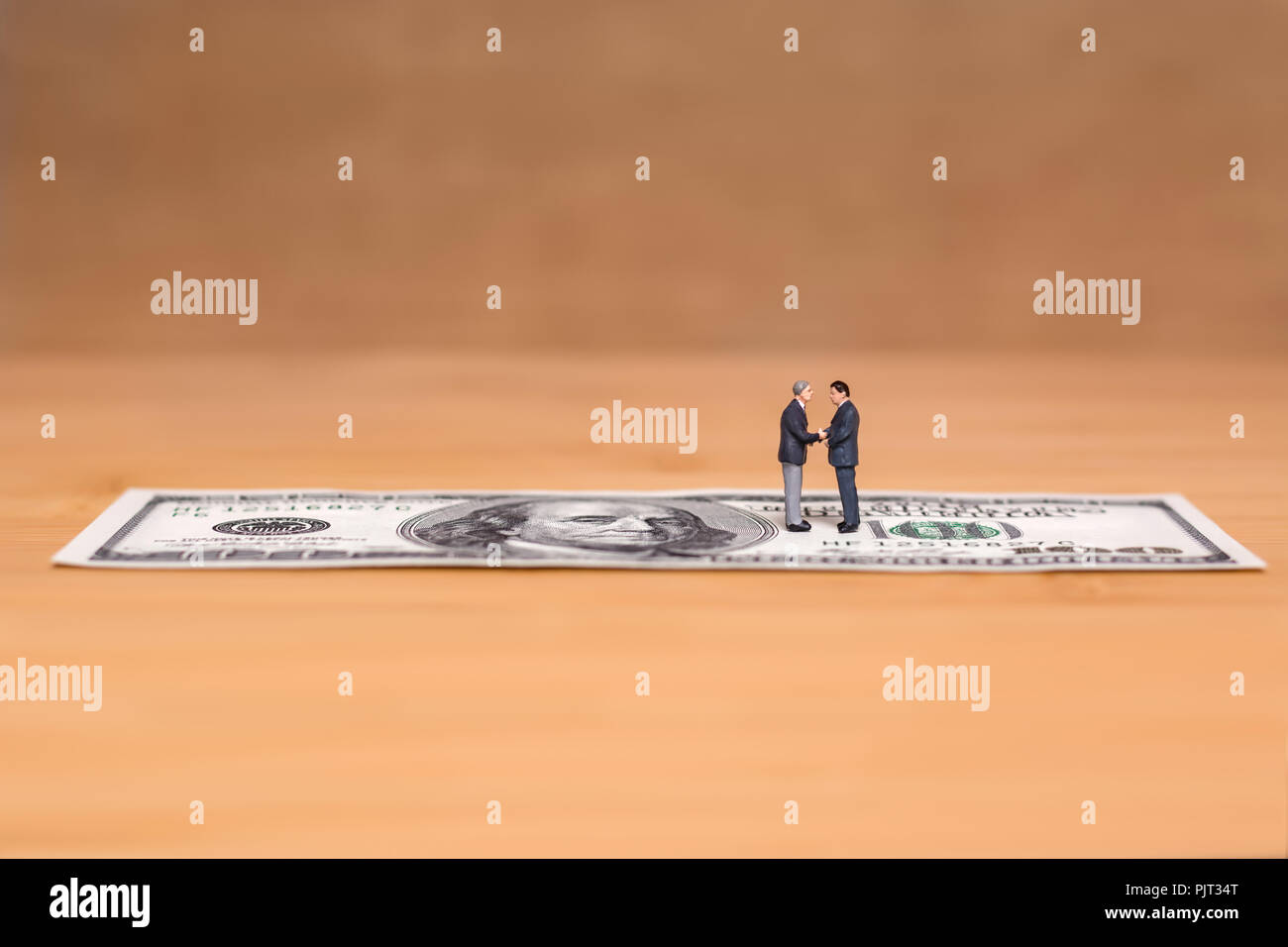 Miniature people and money. Creative concept of a deal. Two businessmen ...